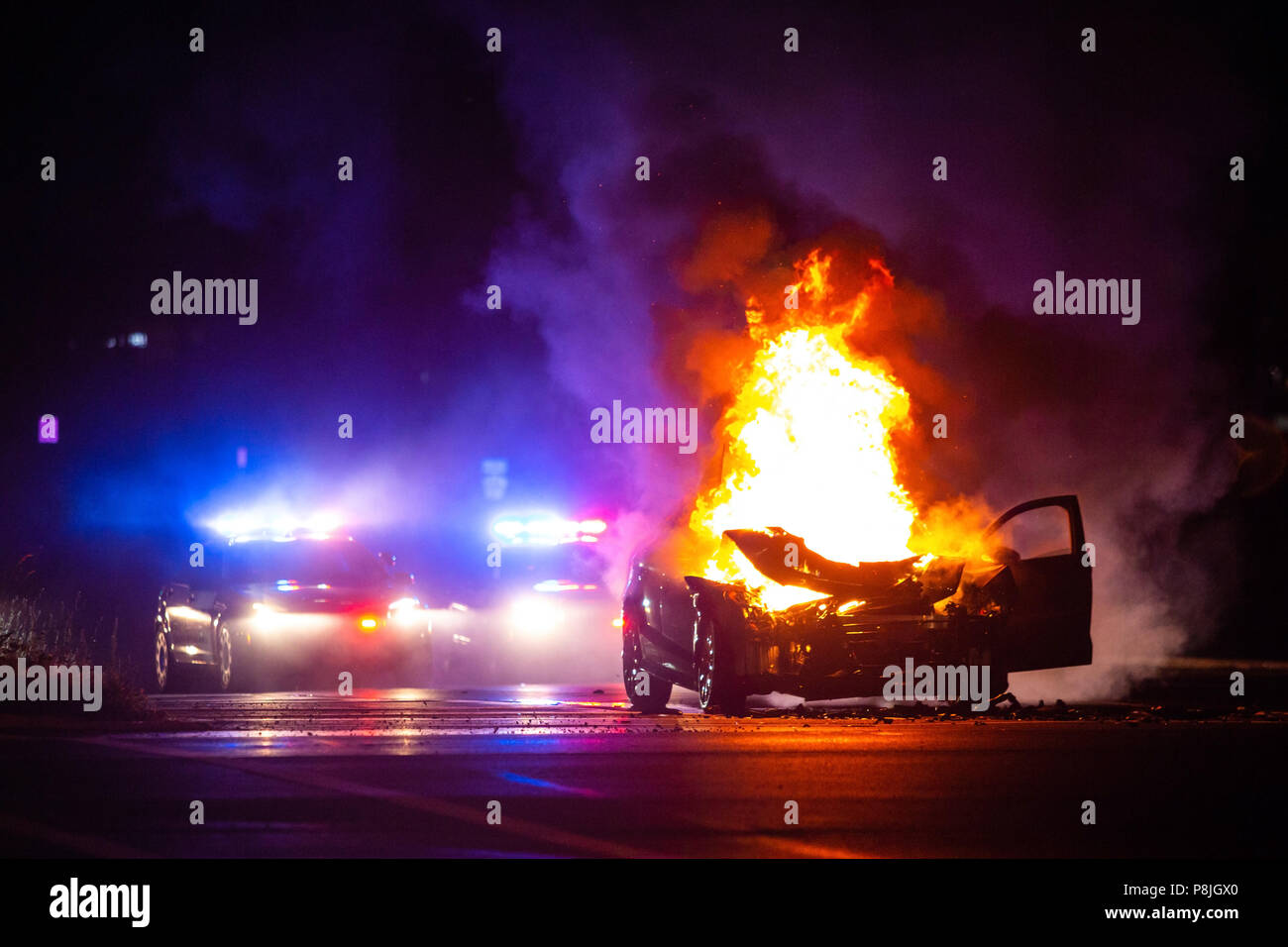 Car on fire at night with police lights in background noone Stock Photo ...