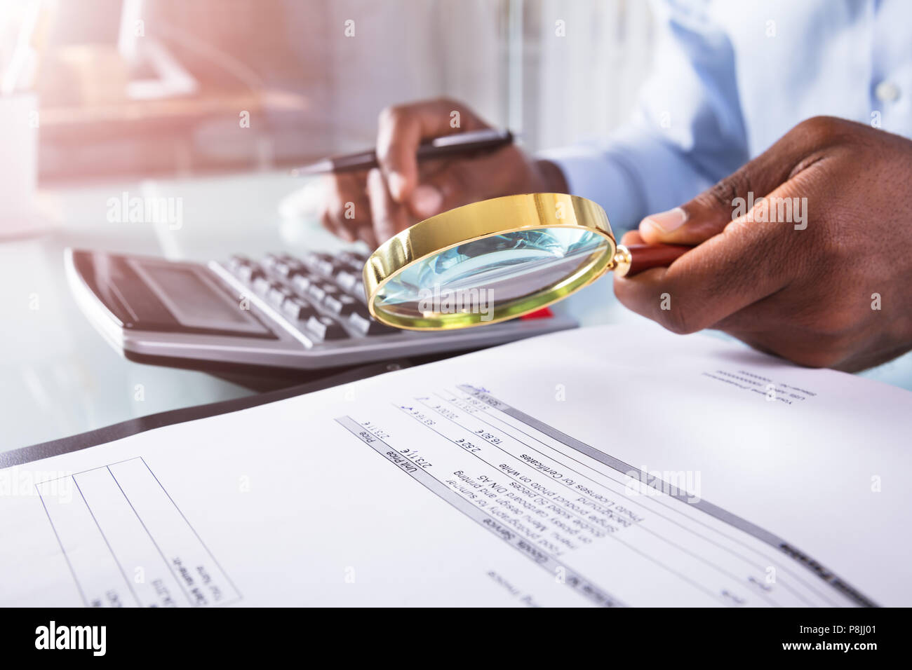Close-up Of A Businessman Holding Magnifying Glass Over Invoice Using ...
