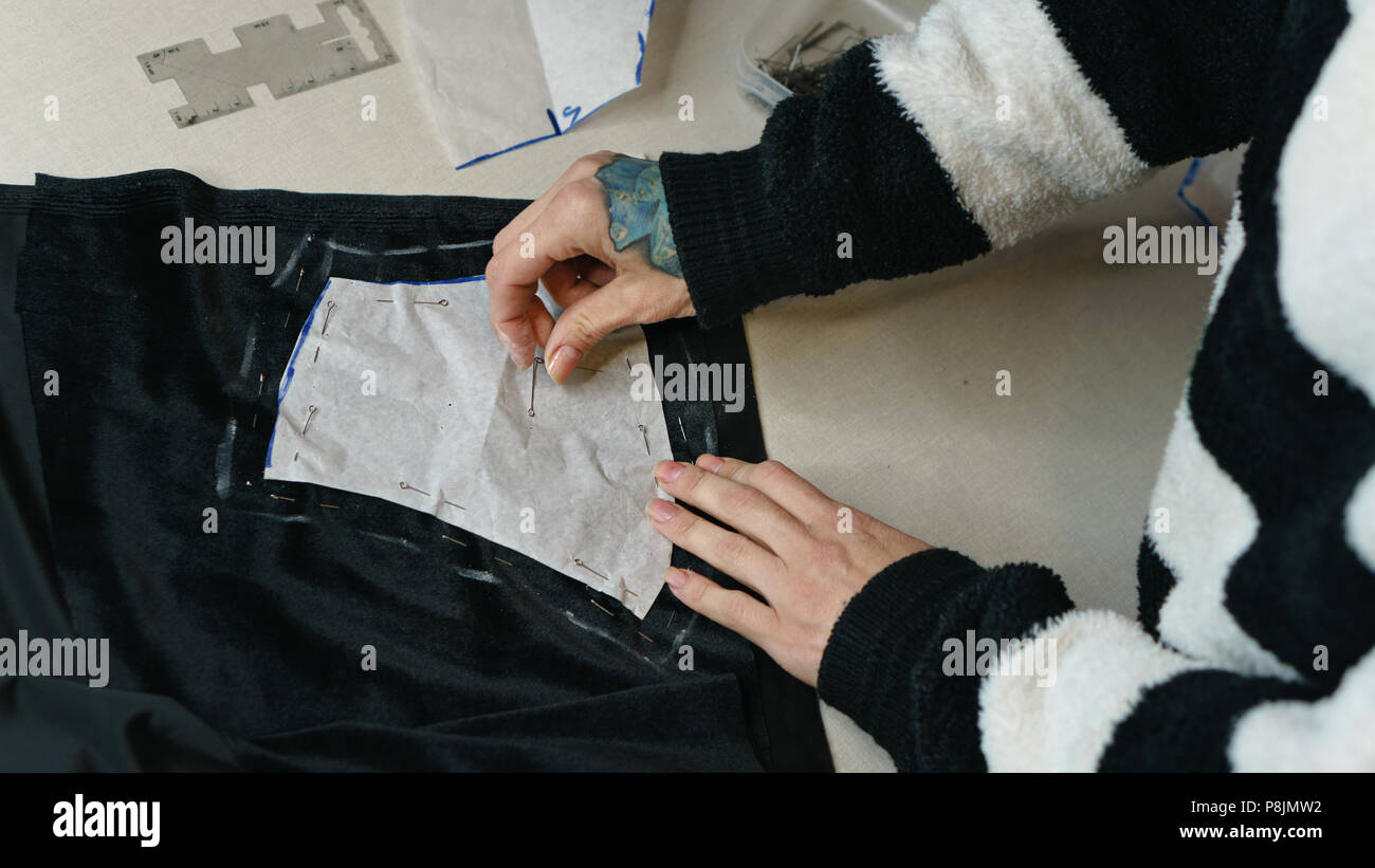 Girl fashion designer draws the pattern on the fabric. Shooting close ...