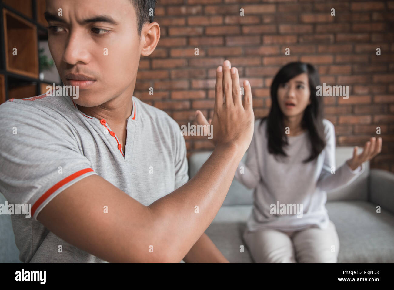Arguing couple sitting apart at home. husband looking aside ignoring ...