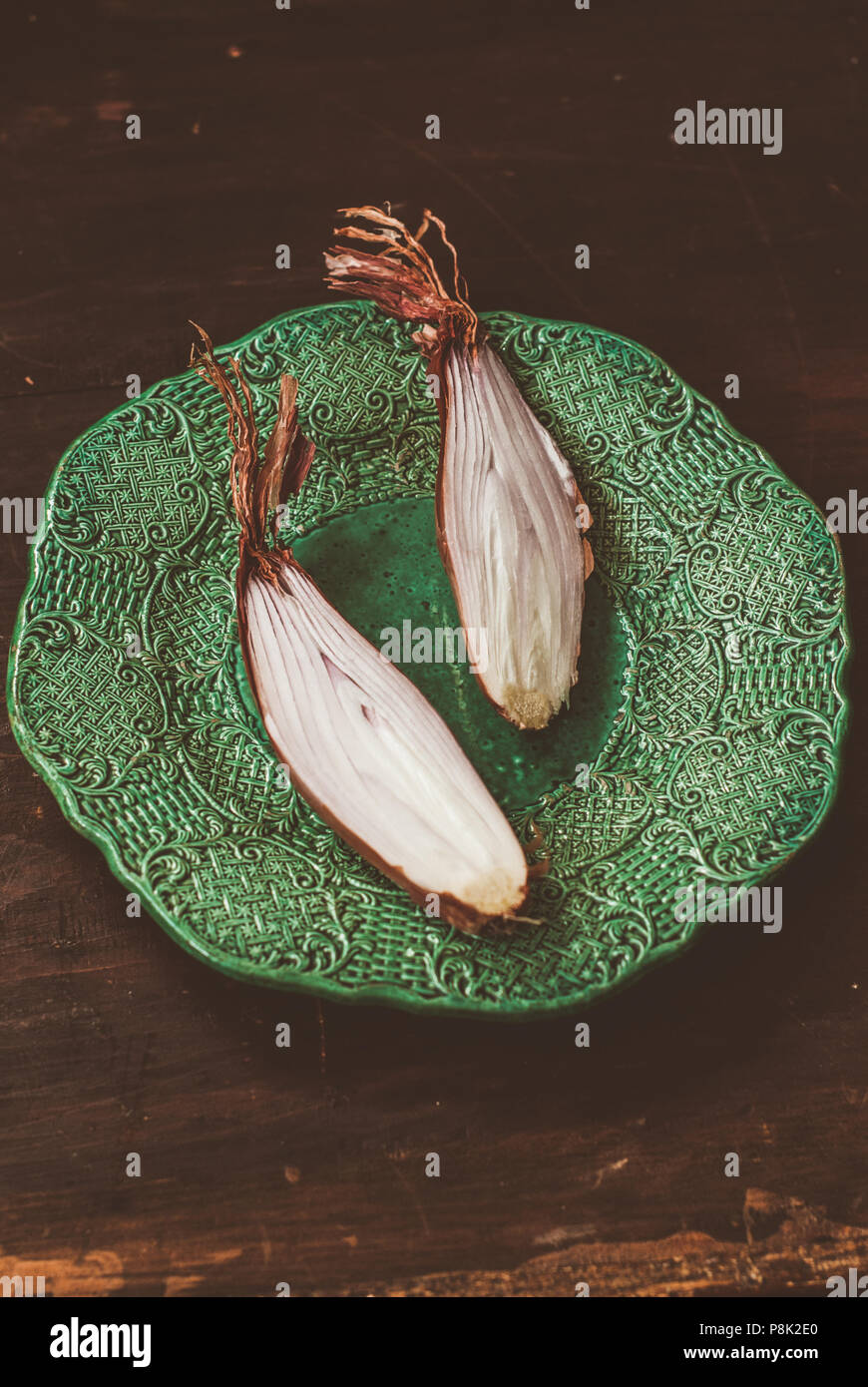A shallot cut in half on a vintage green textured plate Stock Photo - Alamy