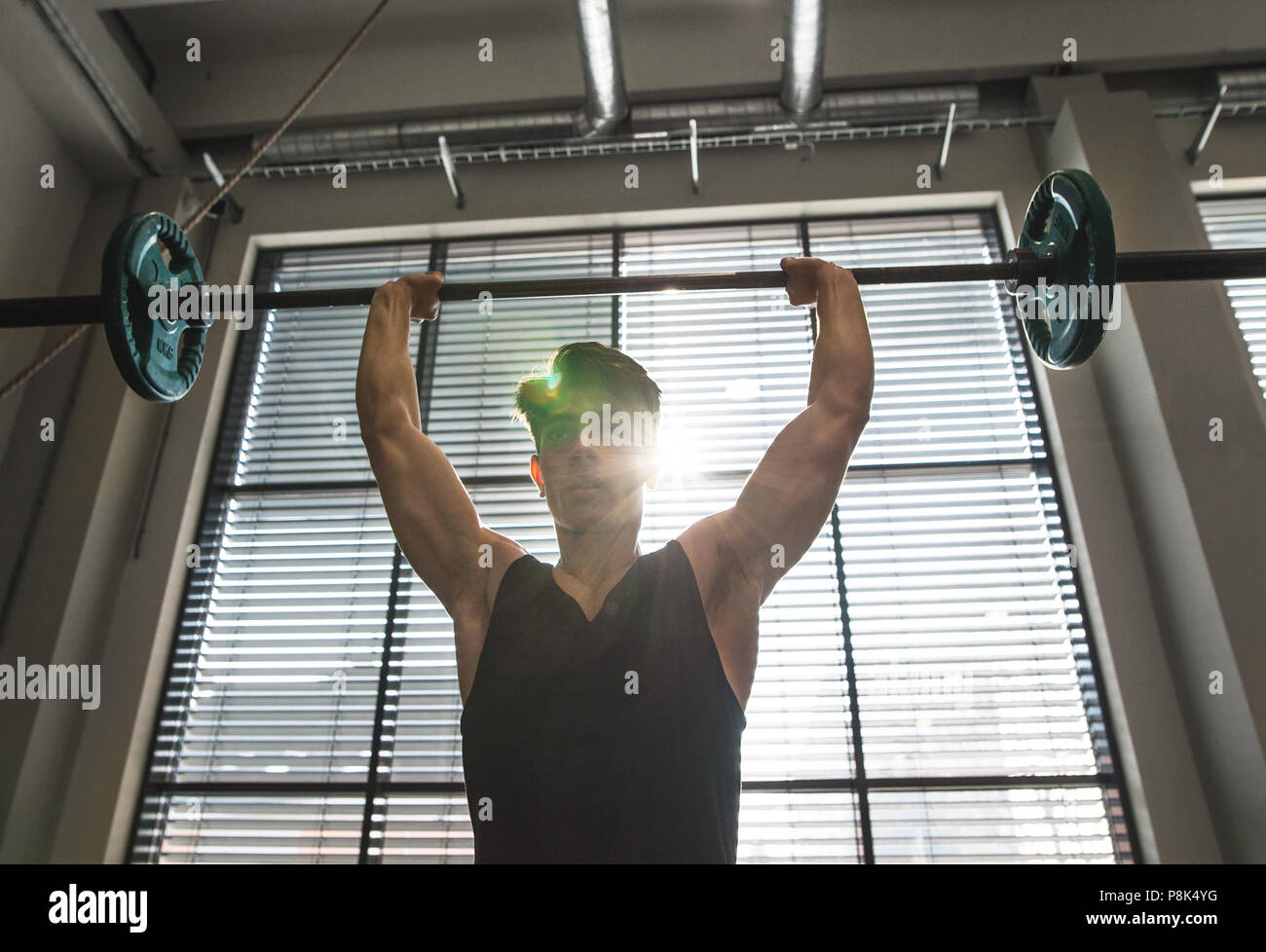 Fit young man in gym working out, lifting barbell Stock Photo - Alamy