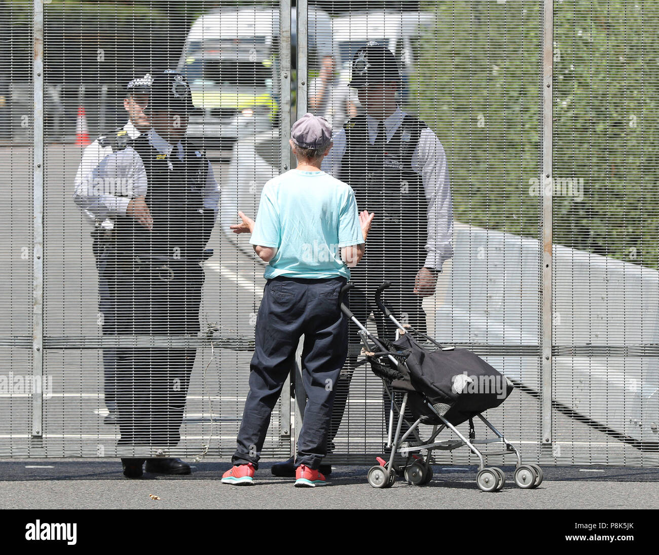Police officers talk to a pedestrian through a fence which is part of ...