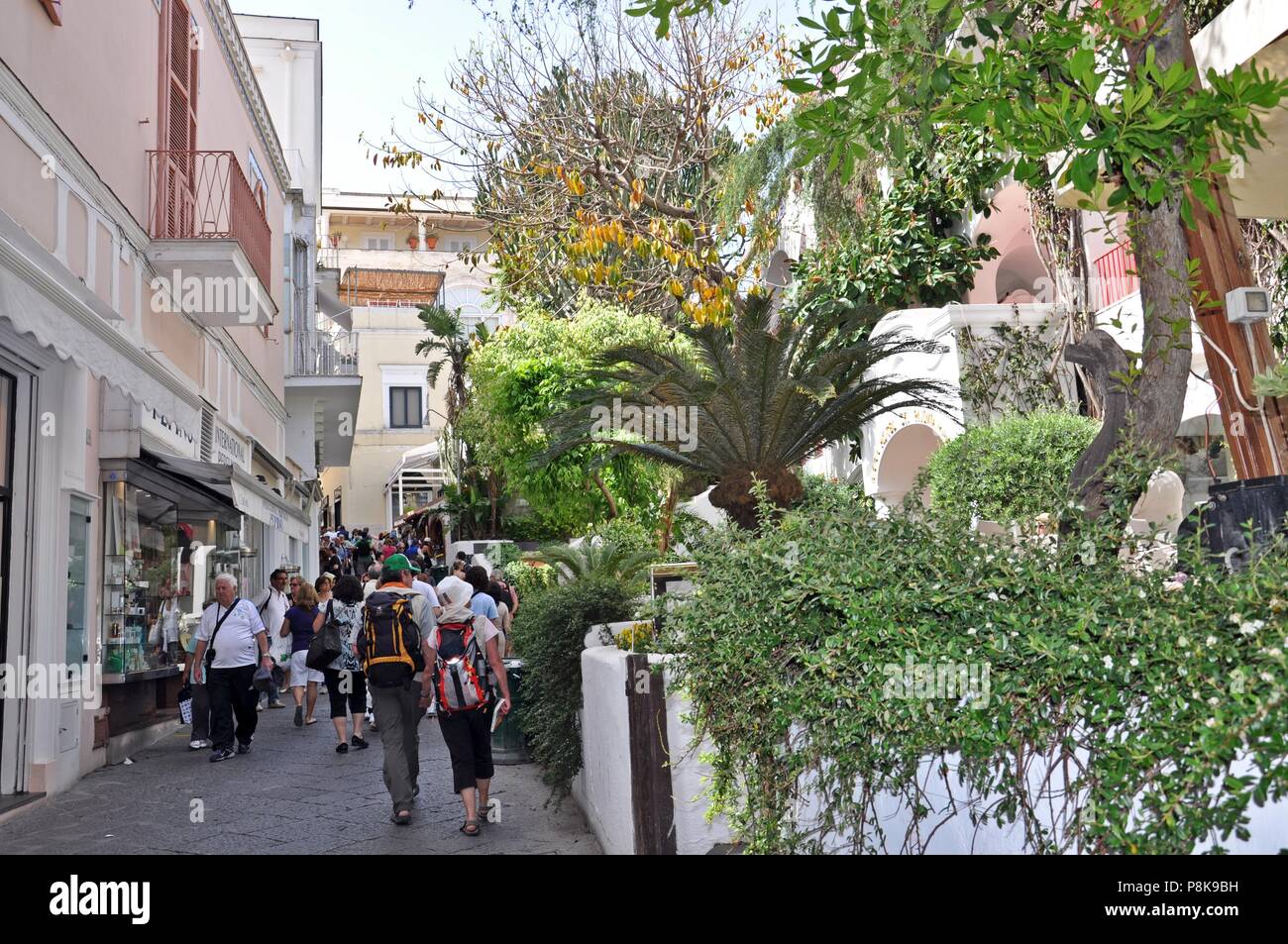 People walking on a narrow shopping street, with shops on the left side ...