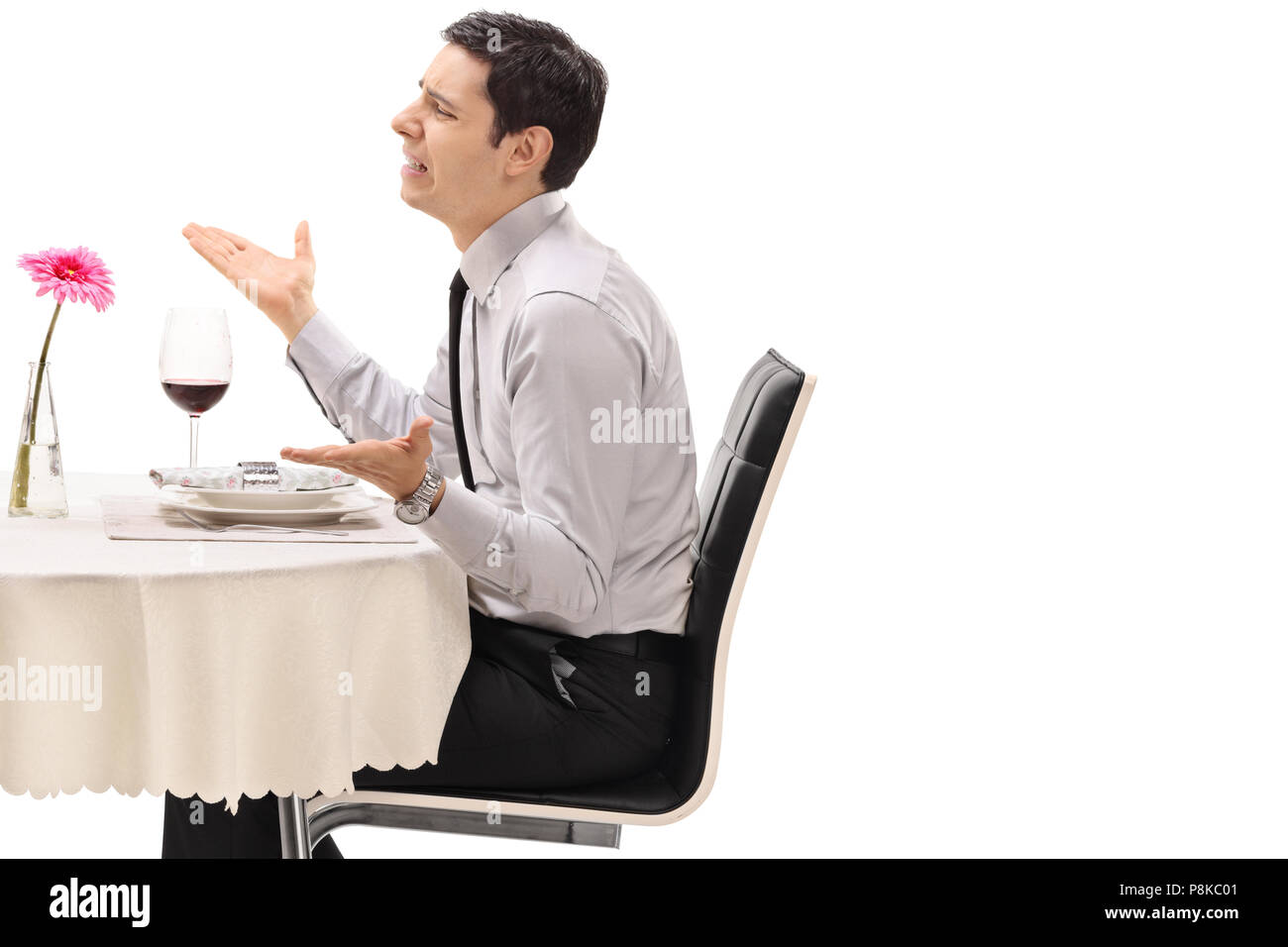 Upset young man sitting at a restaurant table isolated on white ...