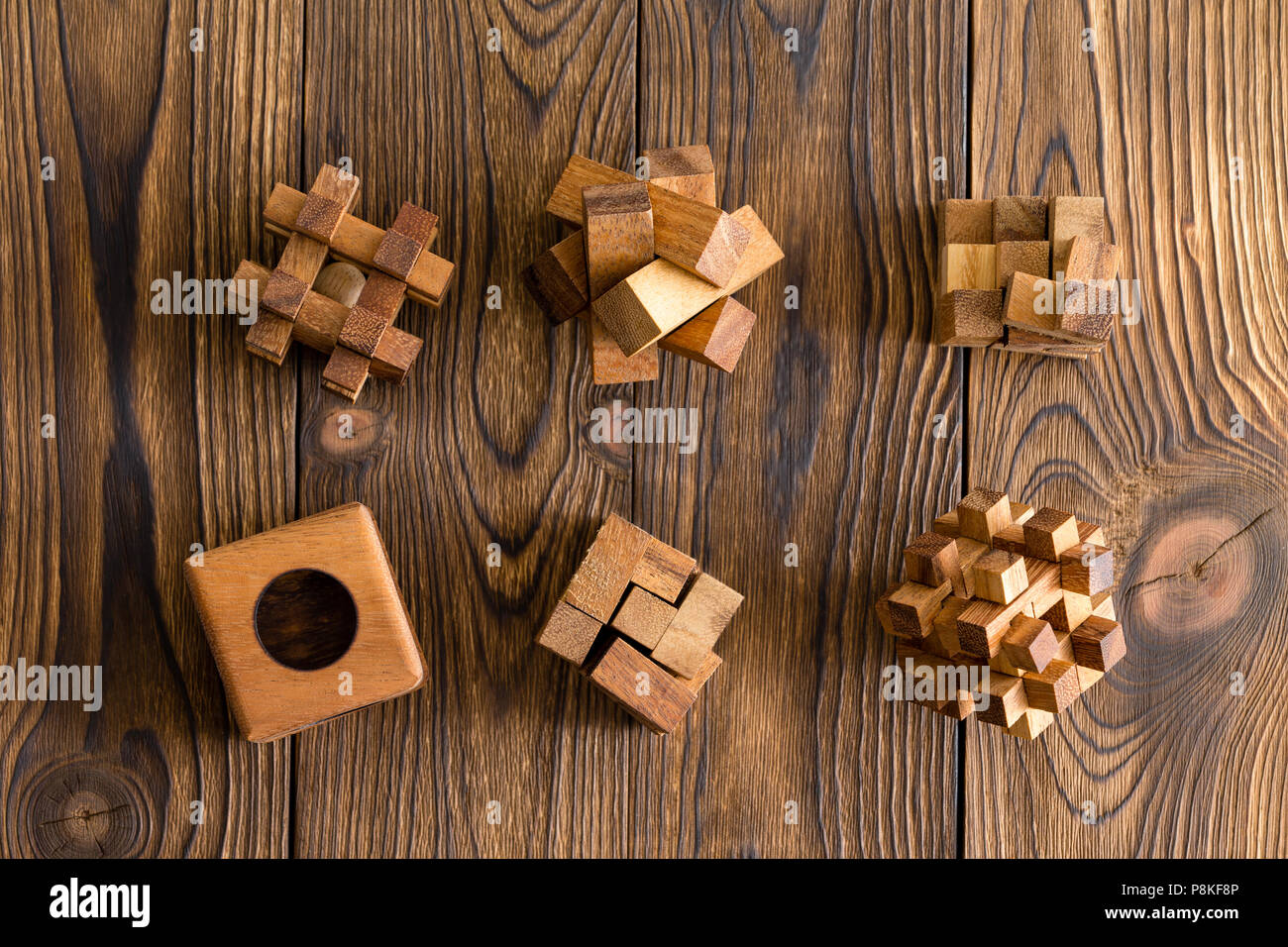Six wooden puzzles of differing complexities arranged in two rows on a ...