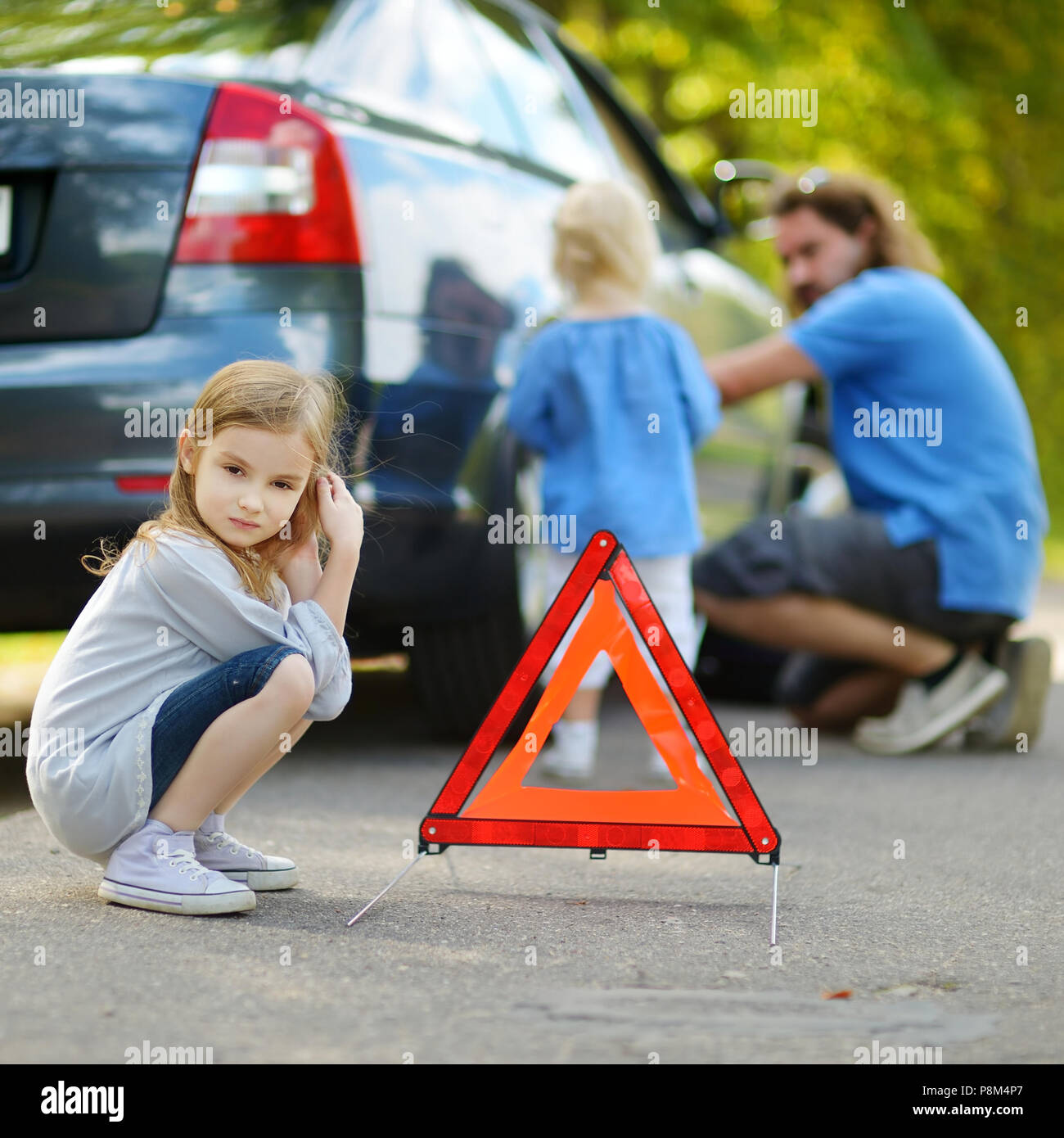 Adorable little girl waiting by the red warning triangle sign while her ...