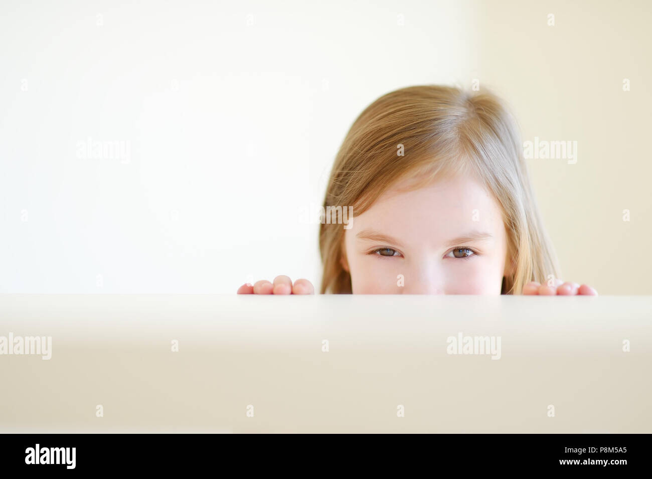 Cute little girl hiding under a table indoors Stock Photo - Alamy