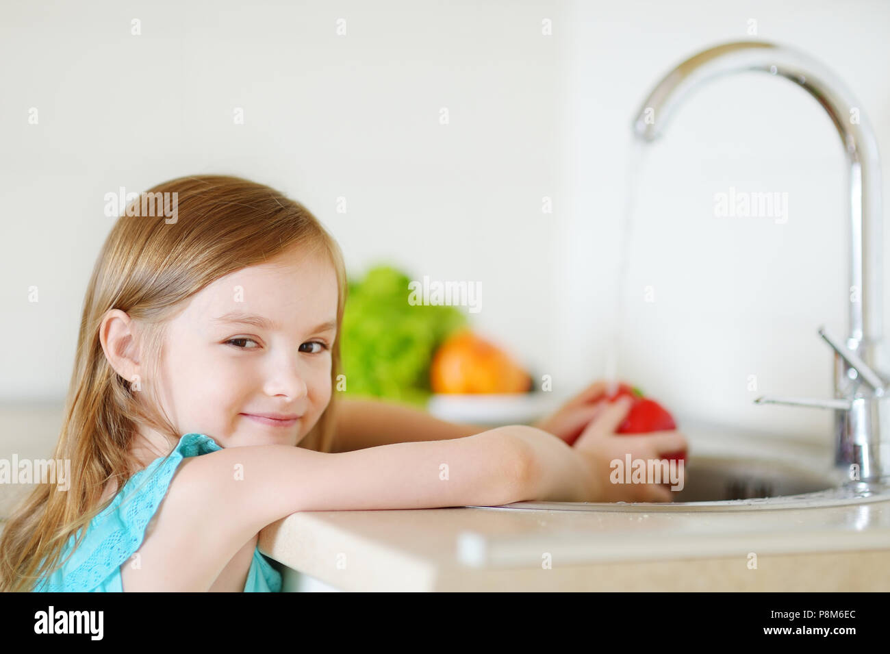 Adorable little girl washing vegetables in a kitchen Stock Photo - Alamy
