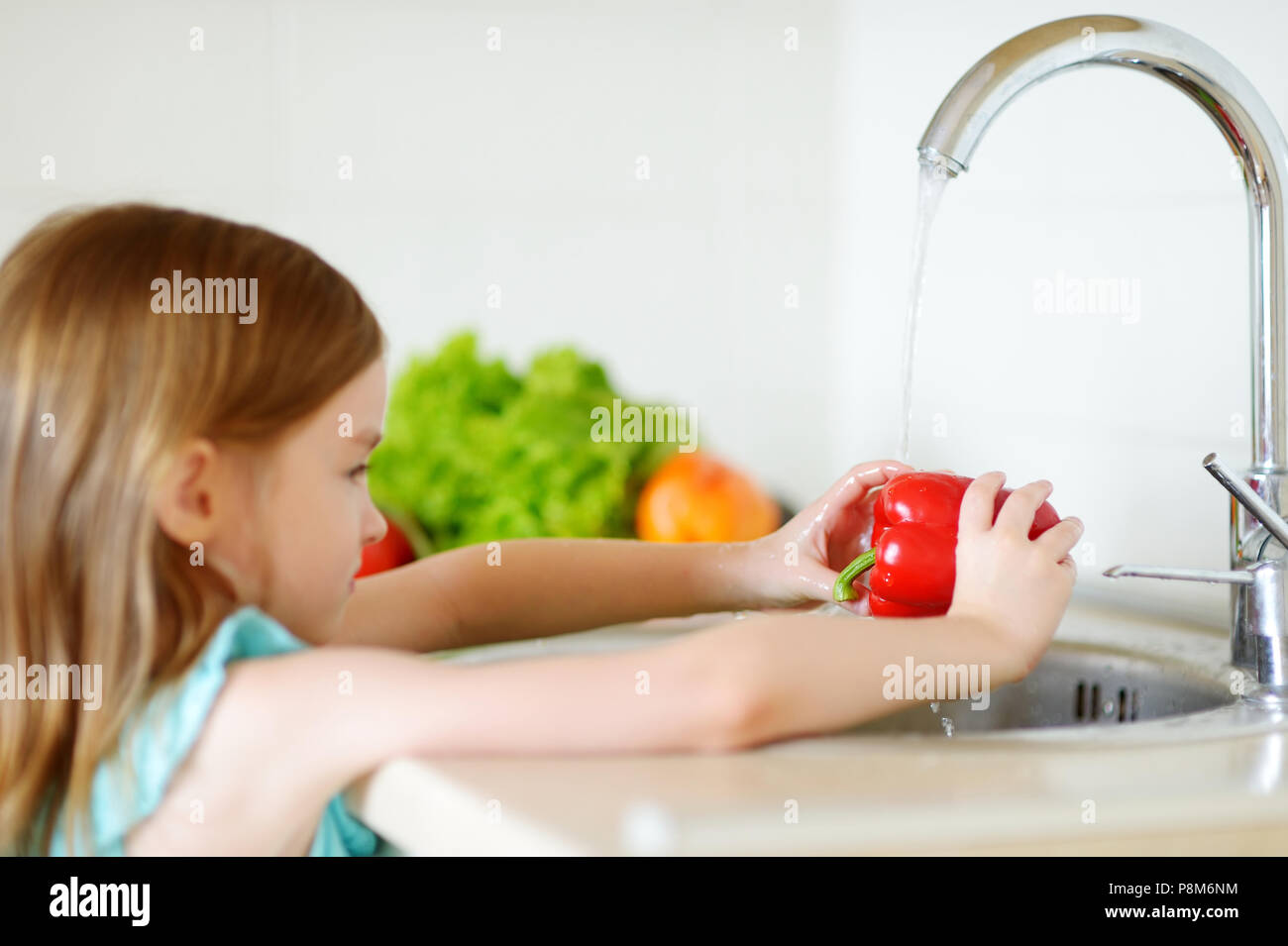 Adorable little girl washing vegetables in a kitchen Stock Photo - Alamy