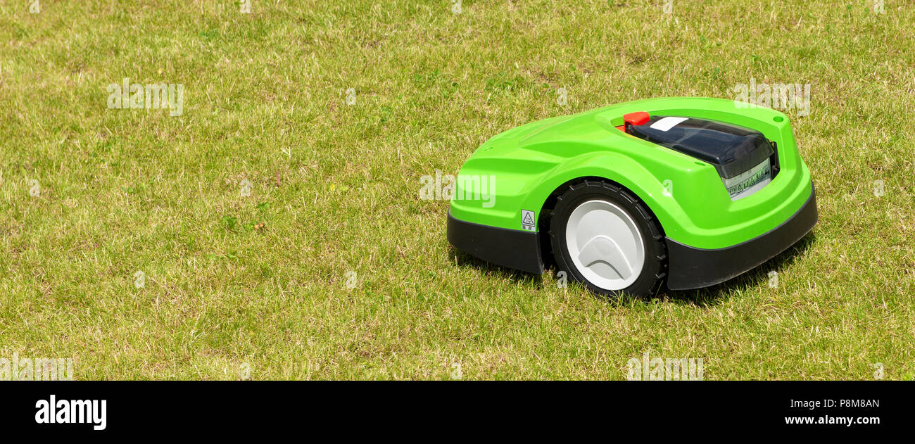 a green robot lawn mower on the lawn Stock Photo - Alamy