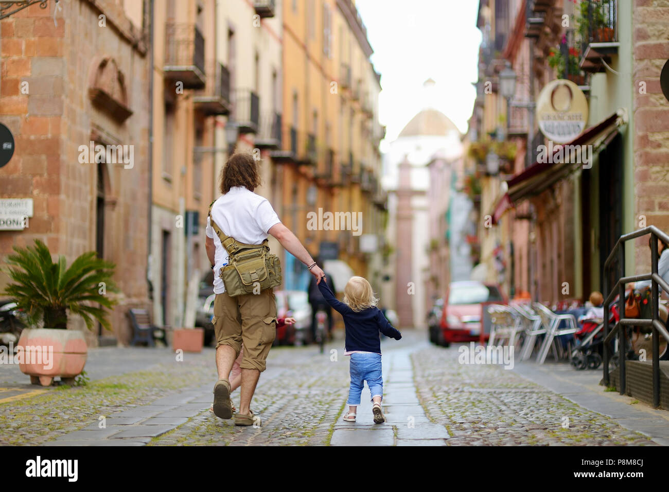Two little sisters and their father on a street of typical italian town ...