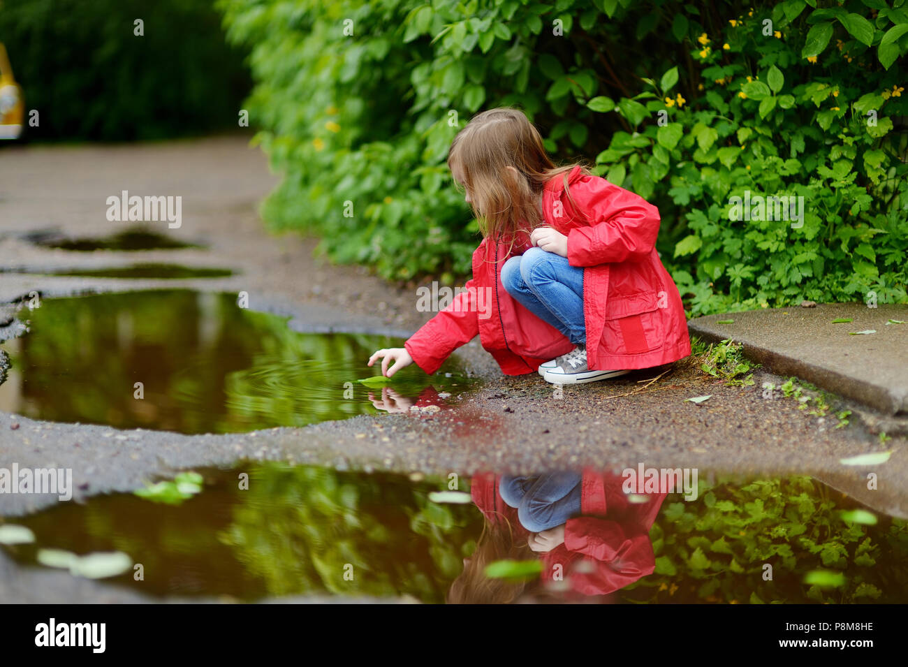 Adorable girl playing in a puddle on rainy summer day Stock Photo - Alamy