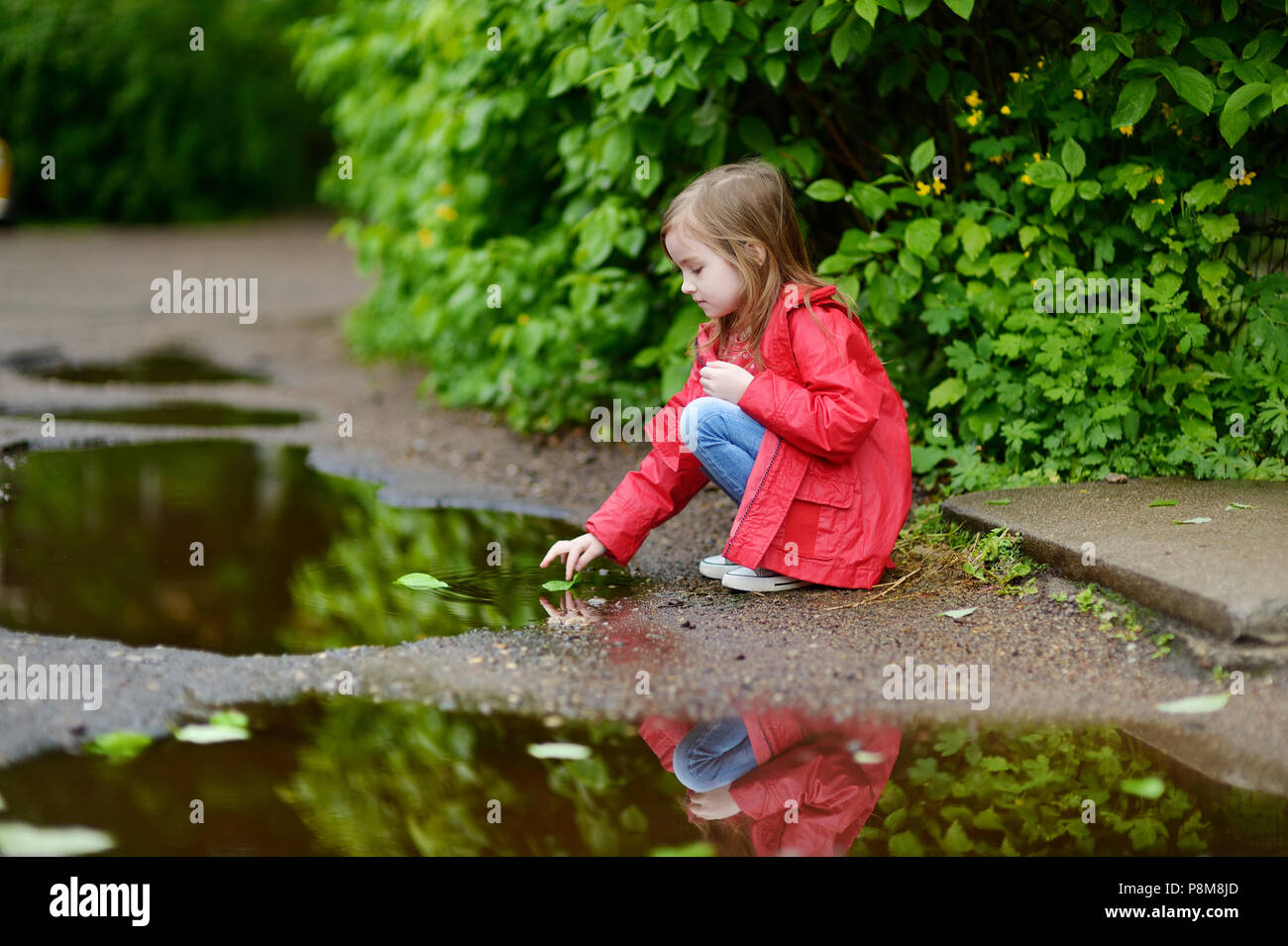 Adorable girl playing in a puddle on rainy summer day Stock Photo - Alamy