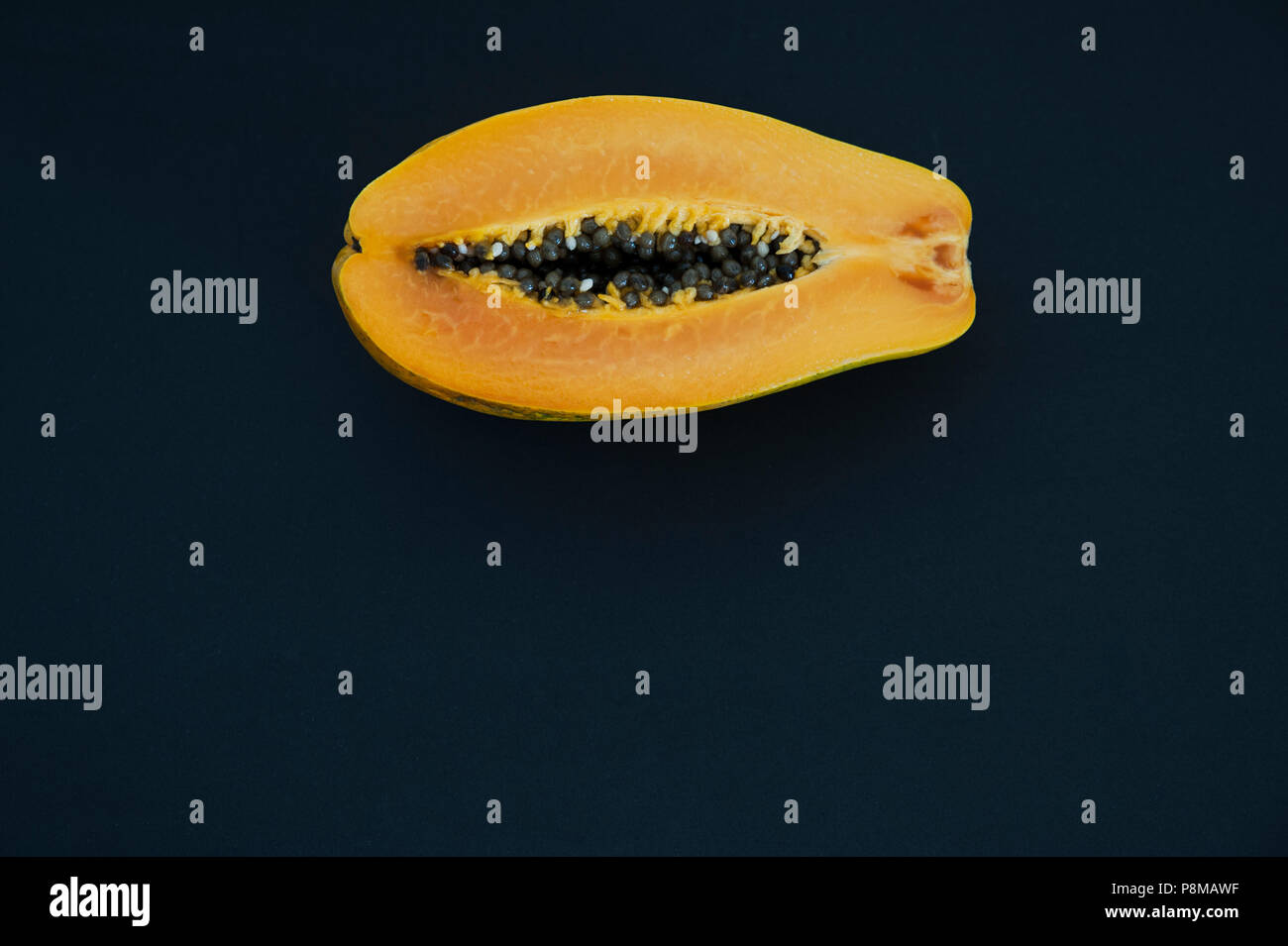 One half of a papaya fruit with seeds and tasty pulp on a dark ...