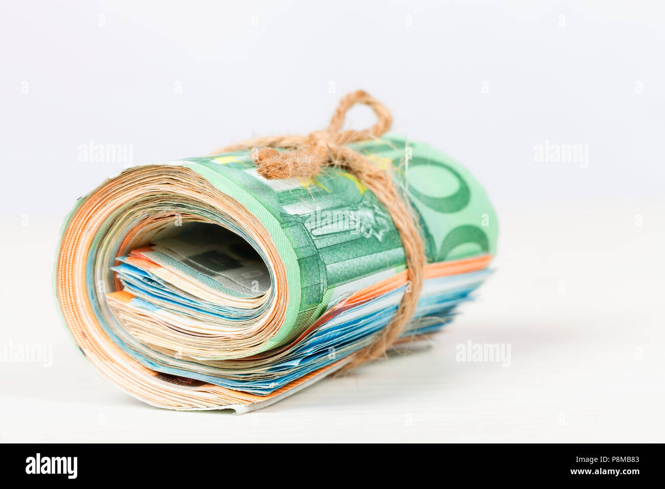 A wad of euro bills rolled and tied with a craft rope Stock Photo - Alamy