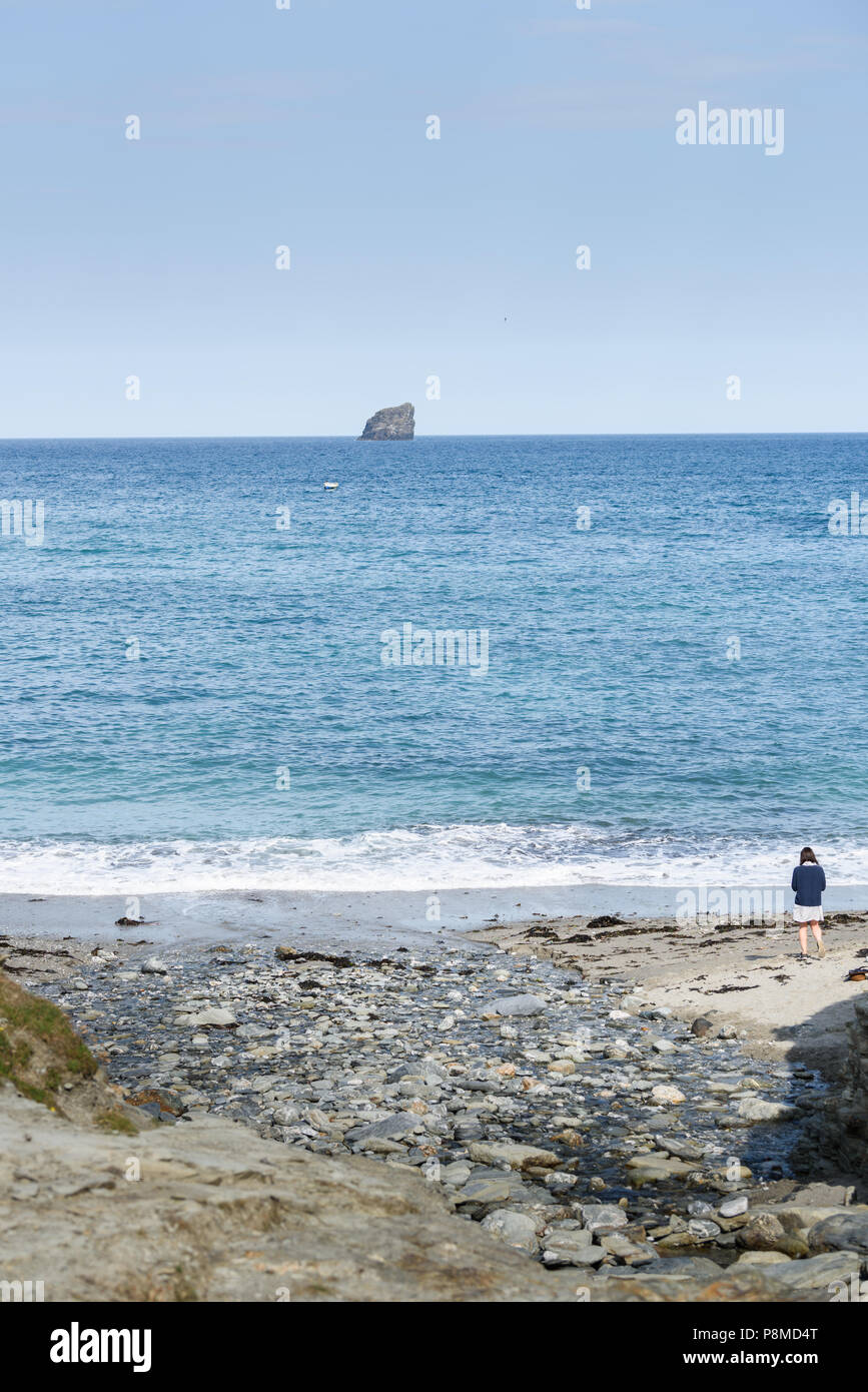 A woman views a calm Atlantic ocean from the shore at Trevellas Porth ...