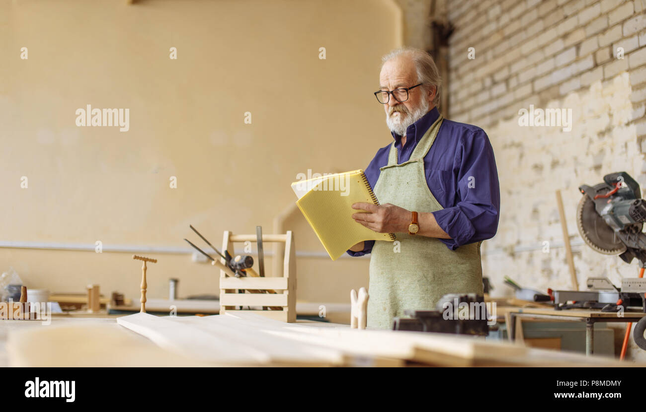 side view image of serious old smart carpenter drawing graph in the ...
