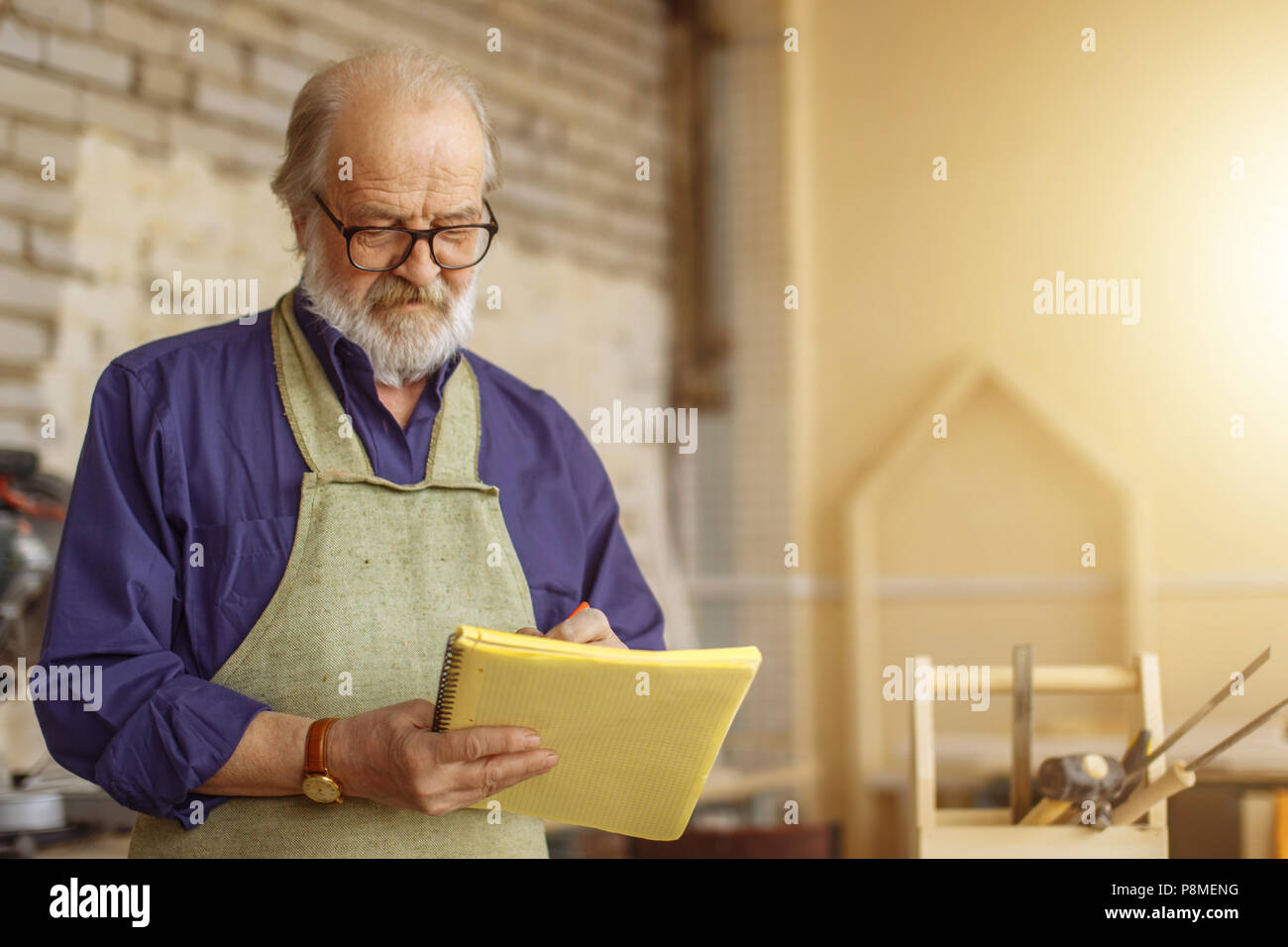 attractive old carpenter working on designs in his workshop.close up ...