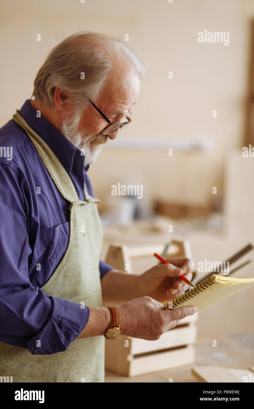 close up cropped side view shot of grey haired grandpa making a drawing ...