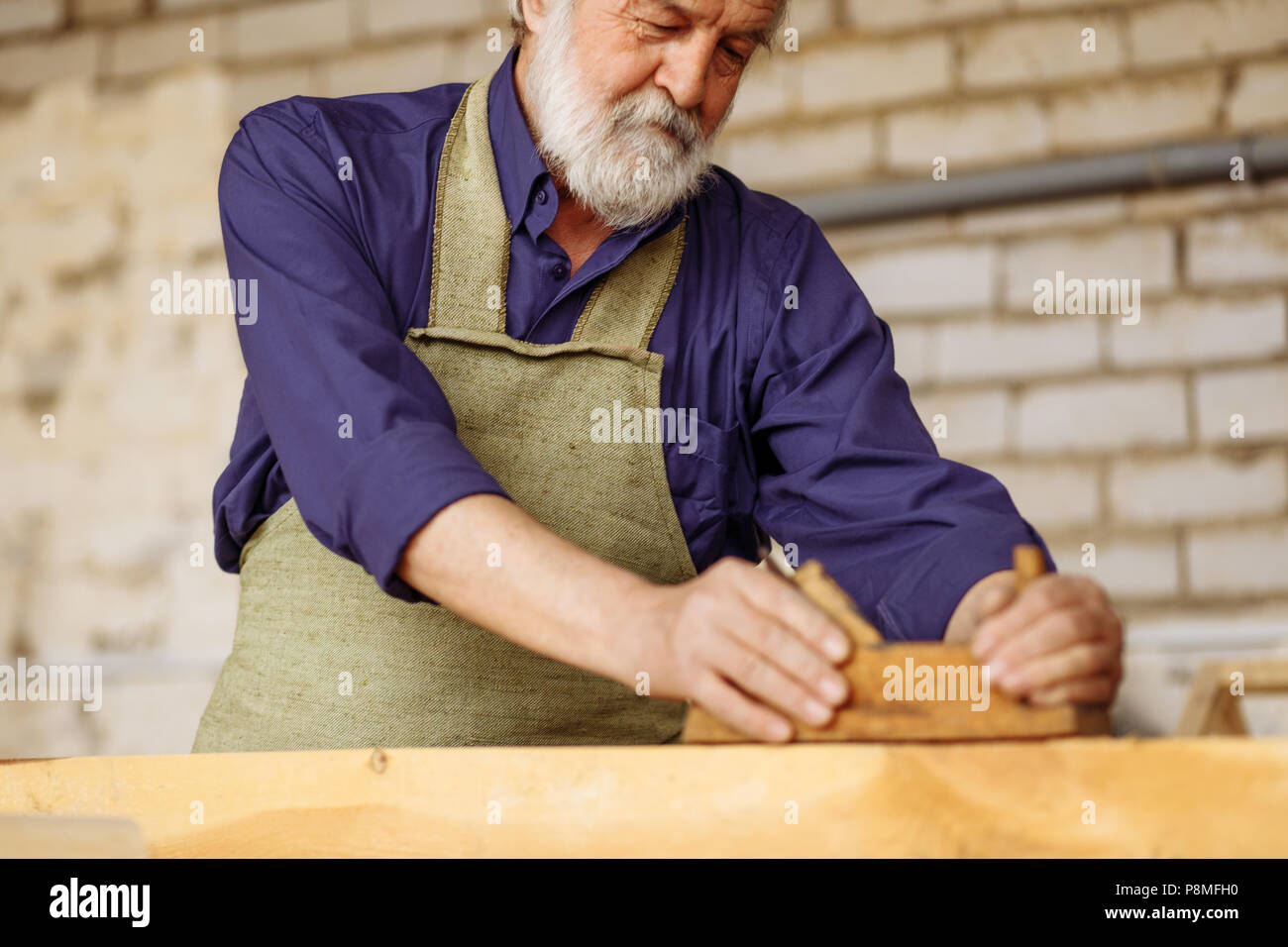 bearded craftsman with grey hair is good at working with planks. close ...