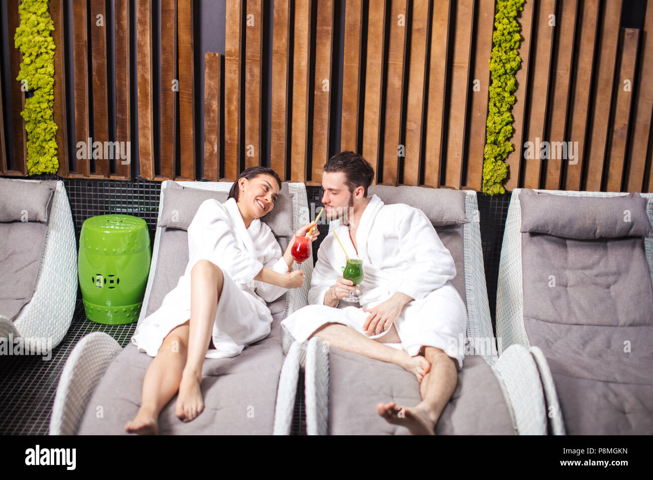 young unshaven black-haired man is tasting his girlfriend's refreshment ...