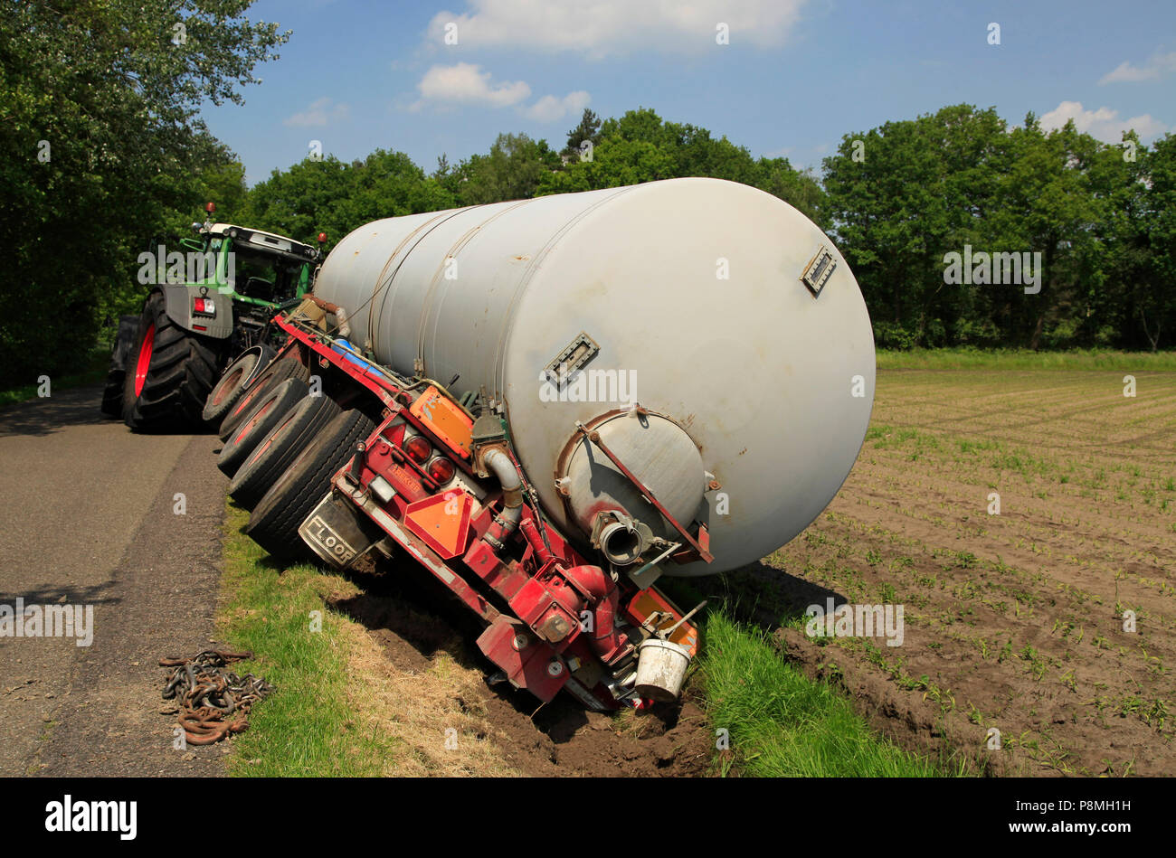 Tractor with a turned over spreadwagon on a small road Stock Photo - Alamy