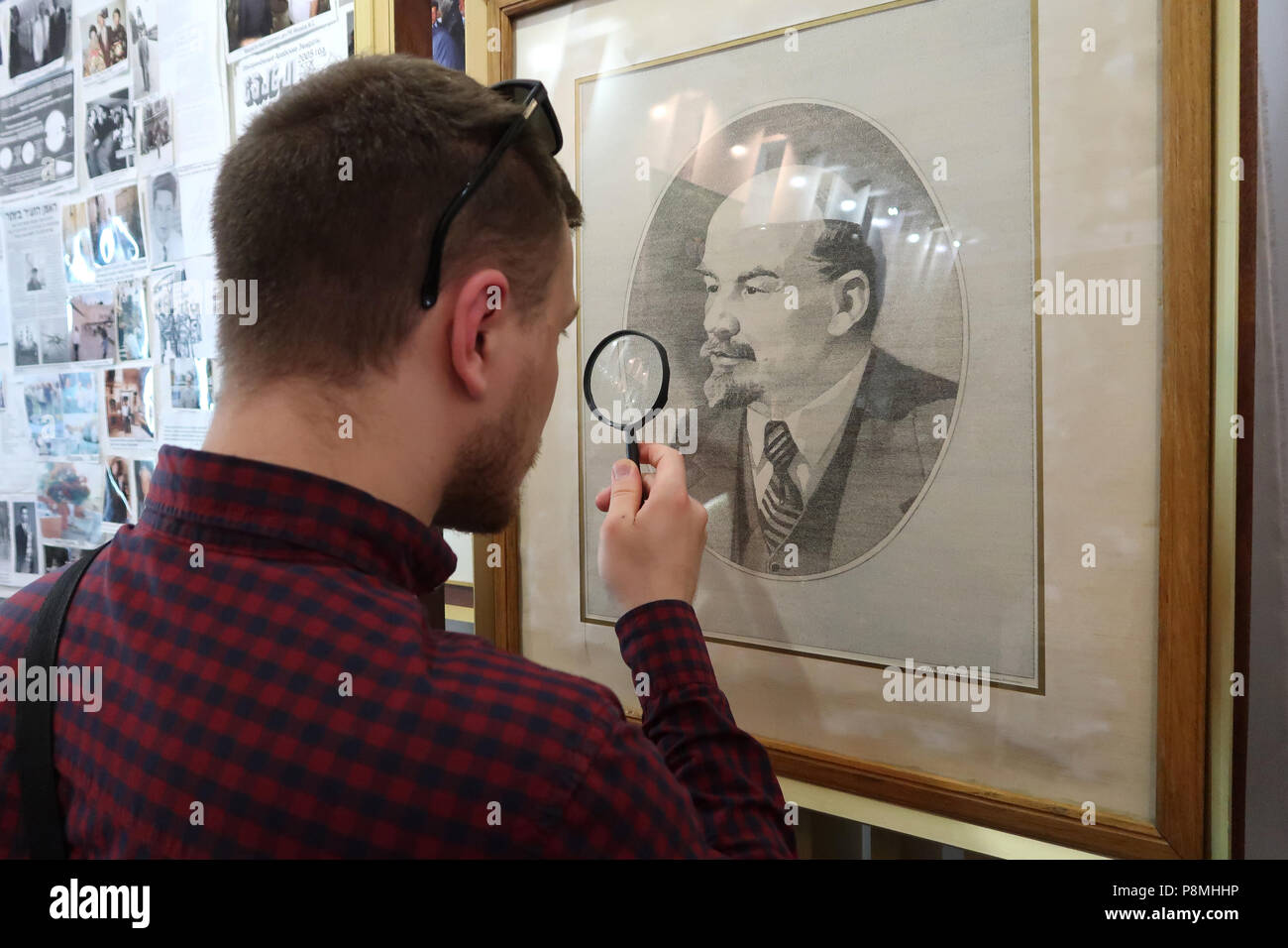 A visitor using a magnifying glass to inspect Vladimir Lenin image made ...