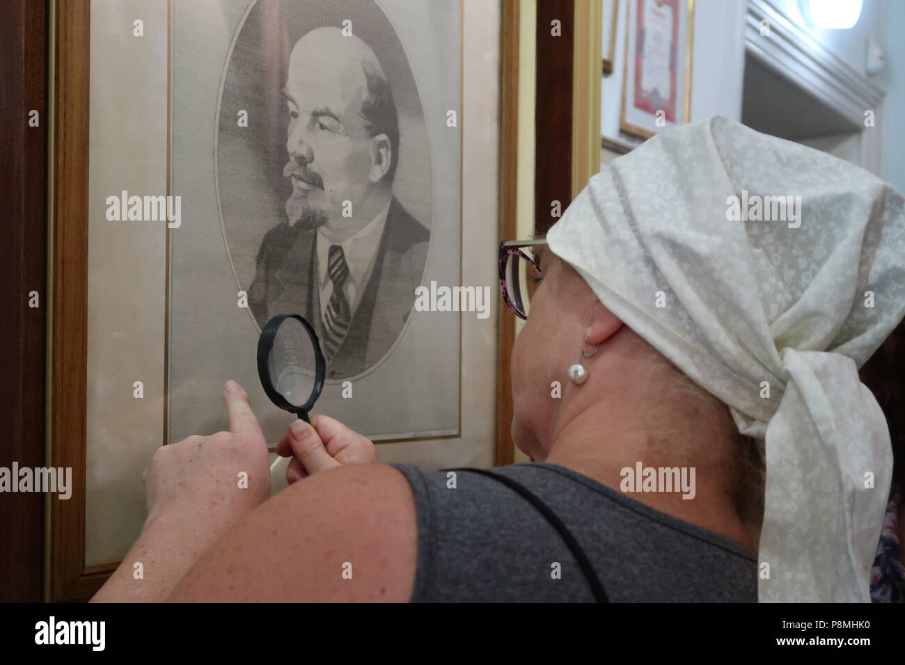 A visitor using a magnifying glass to inspect Vladimir Lenin image made ...