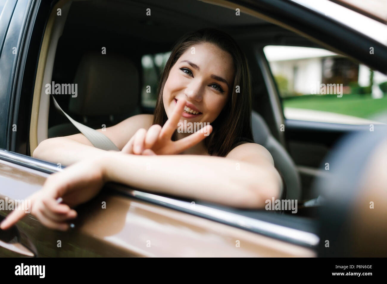 Smiling young woman doing peace sign in car Stock Photo - Alamy