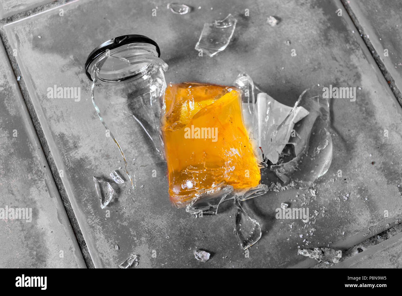 Broken marmalade glass jar on tile floor Stock Photo - Alamy