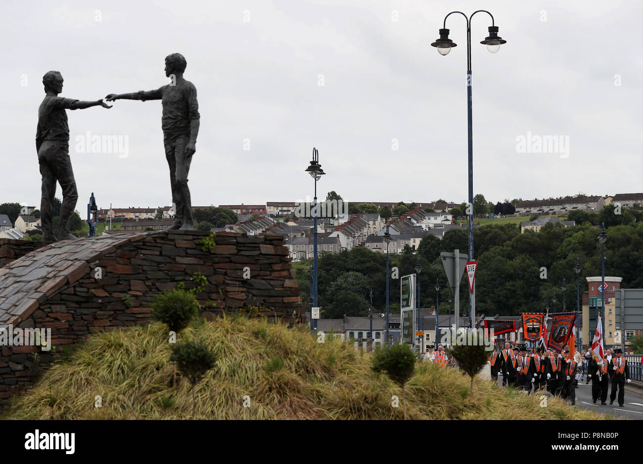 An Orange Order parade approaches the 'Hands Across the Divide' statue ...