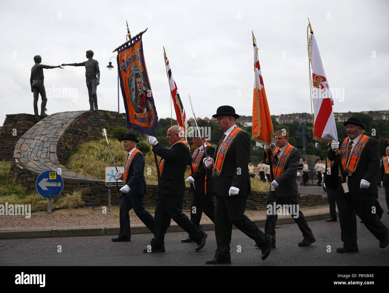 An Orange Order parade passes the 'Hands Across the Divide' statue in ...
