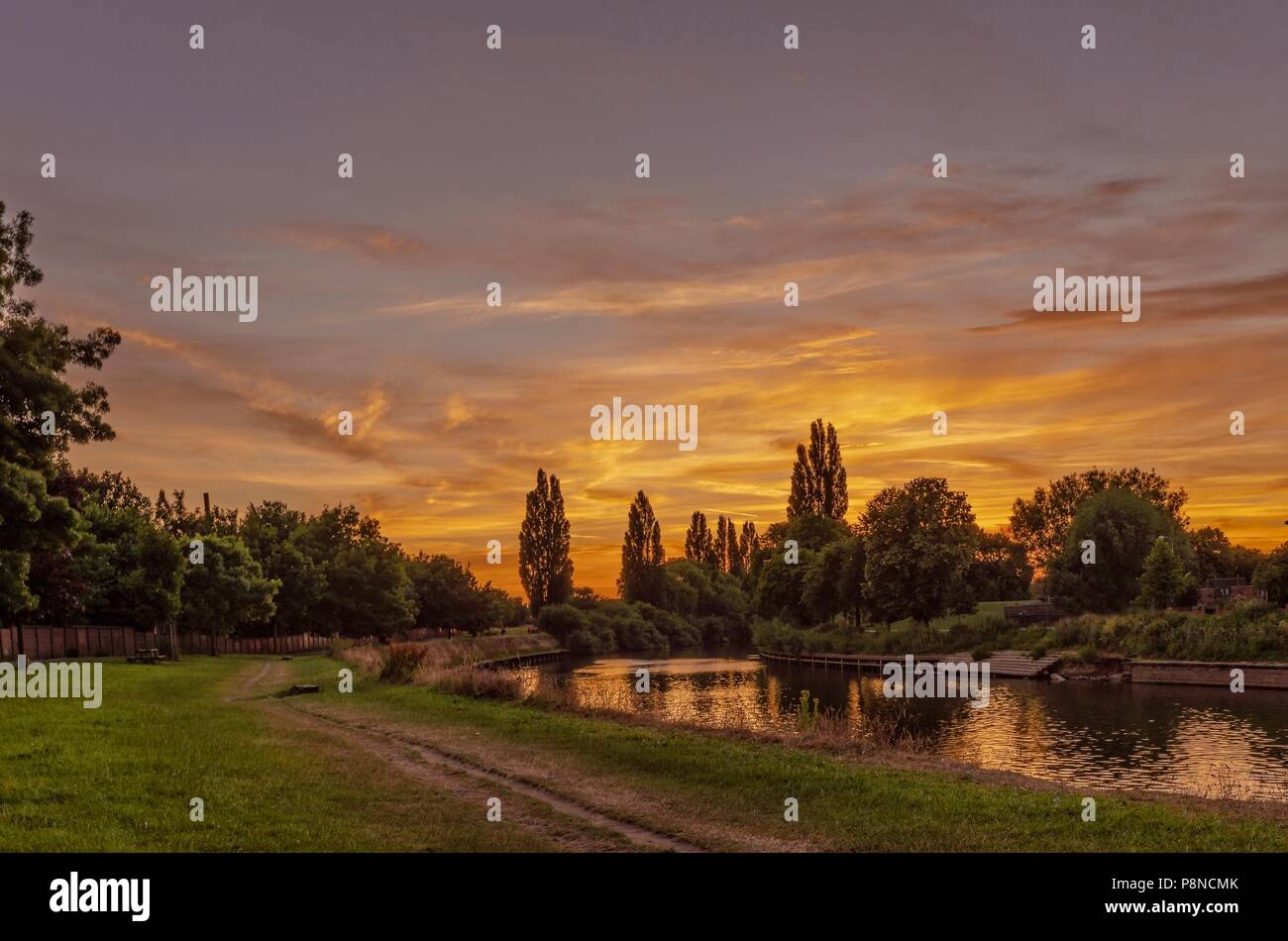 A dramatic sunset over a bend in the River Ouse in York. A path runs ...