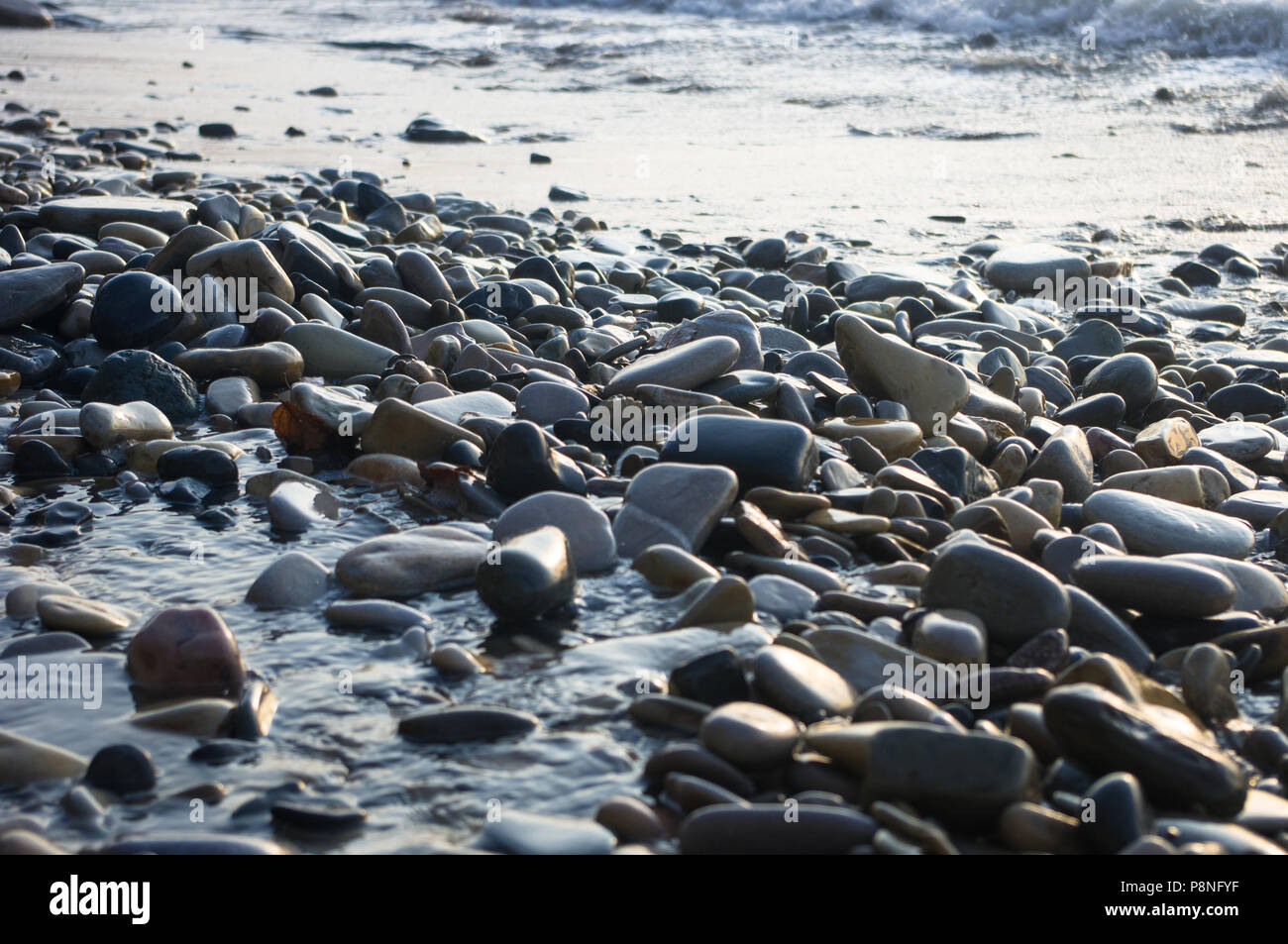 pebble stones on the sea beach on a warm summer day, the rolling waves ...