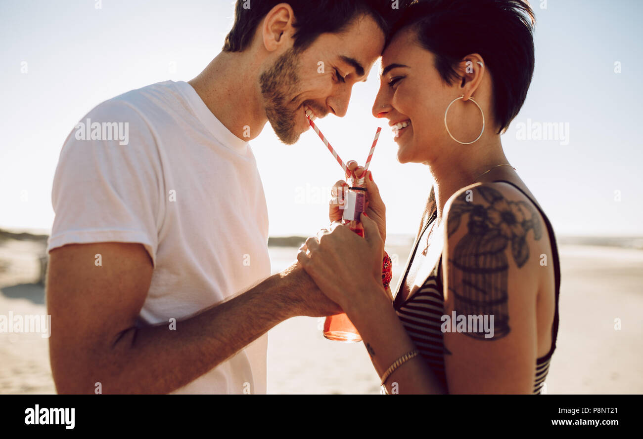 Young happy couple outdoors drinking cold drink from glass bottle with ...