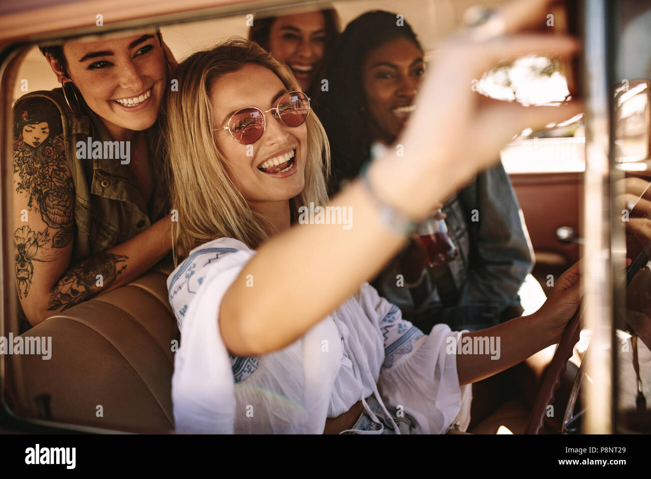 Group of young friends taking selfie in the car. Woman driving a car ...