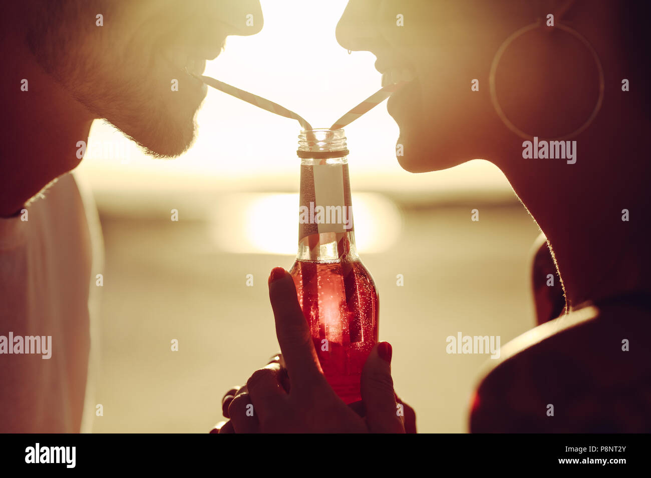 Close up of romantic couple drinking soft drink with straws from one ...