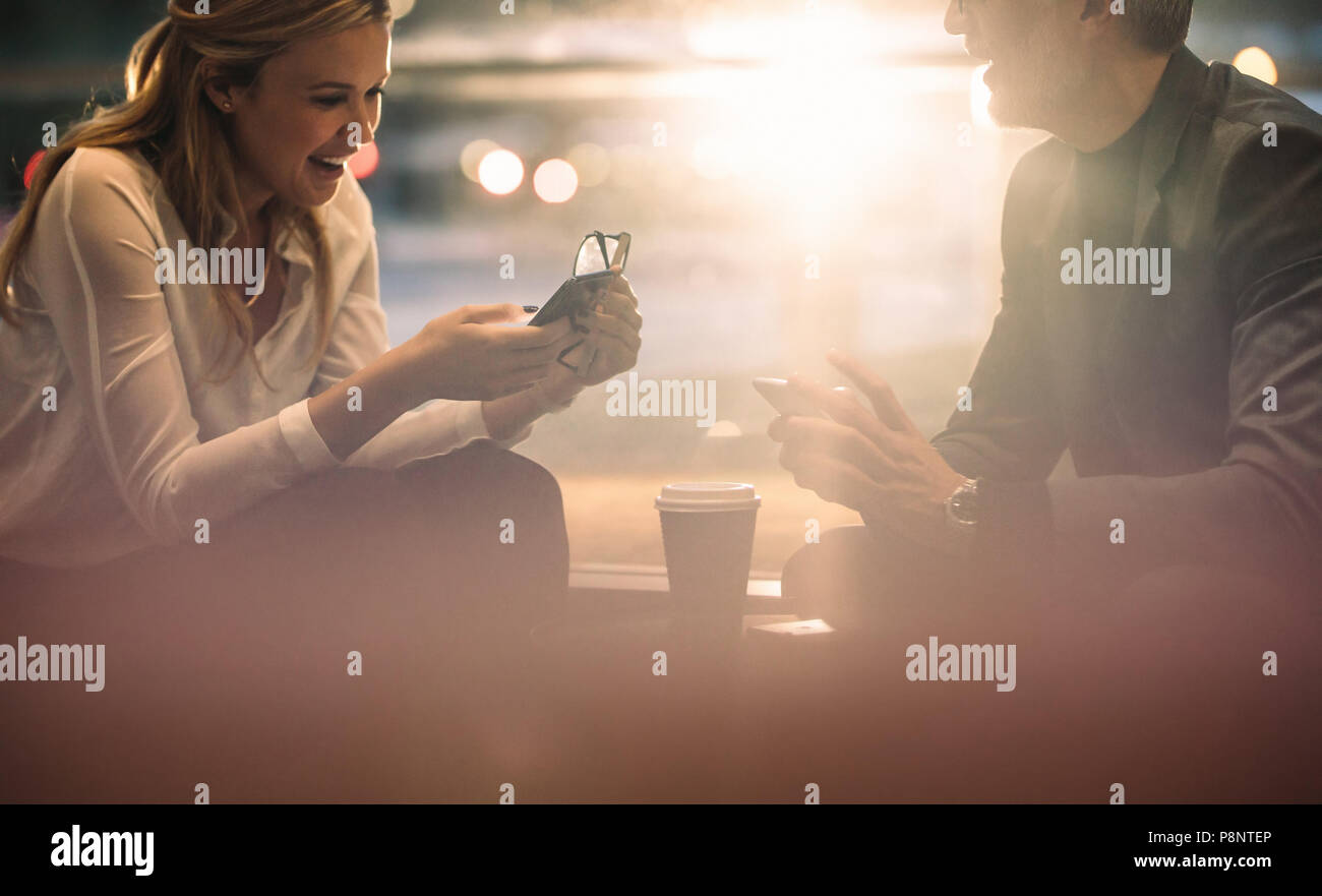 Smiling business colleagues using their smart phones during coffee ...