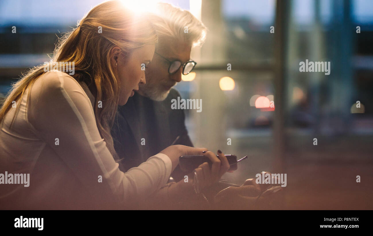Business colleagues sitting together in office lobby and using their ...
