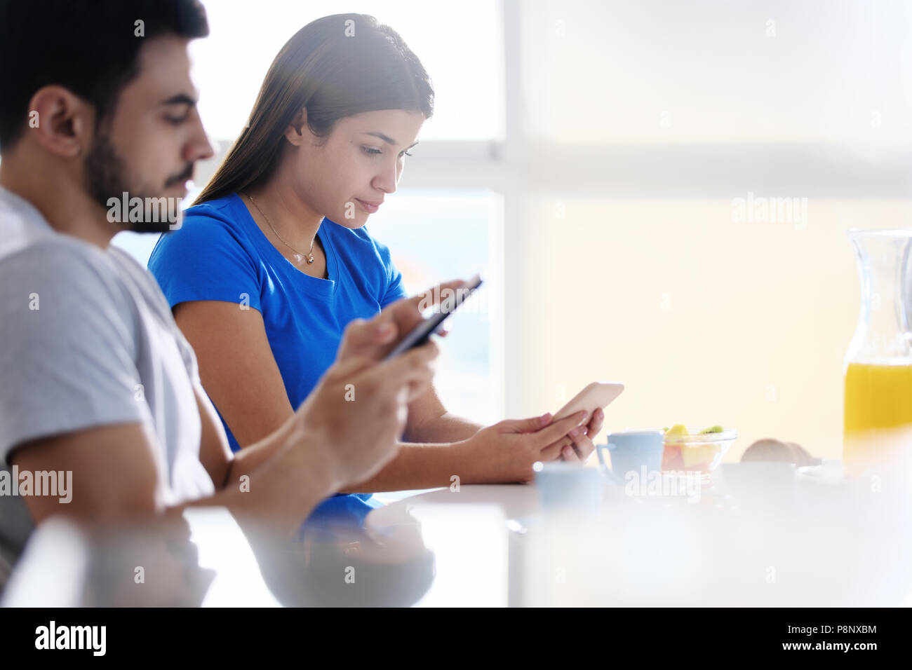 Partners Using Phone While Eating Breakfast Together Stock Photo - Alamy