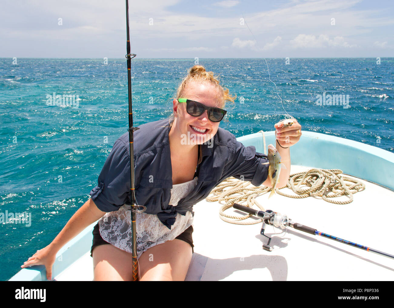Woman proudly displays her deep sea fish catch on a boat Stock Photo ...