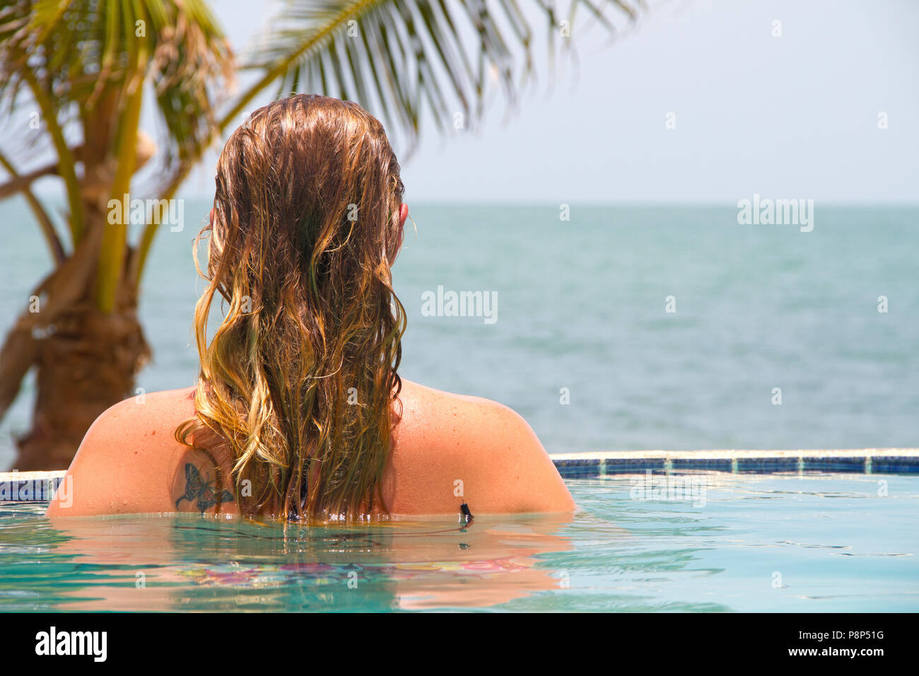 Woman in an infinity pool looks out at the ocean Stock Photo - Alamy