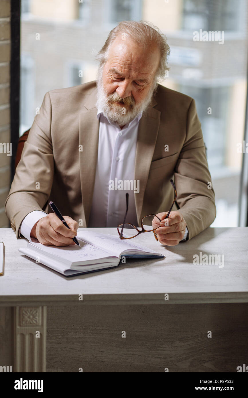 old man pleasant man is writing his ideas in the notebook indoors Stock ...