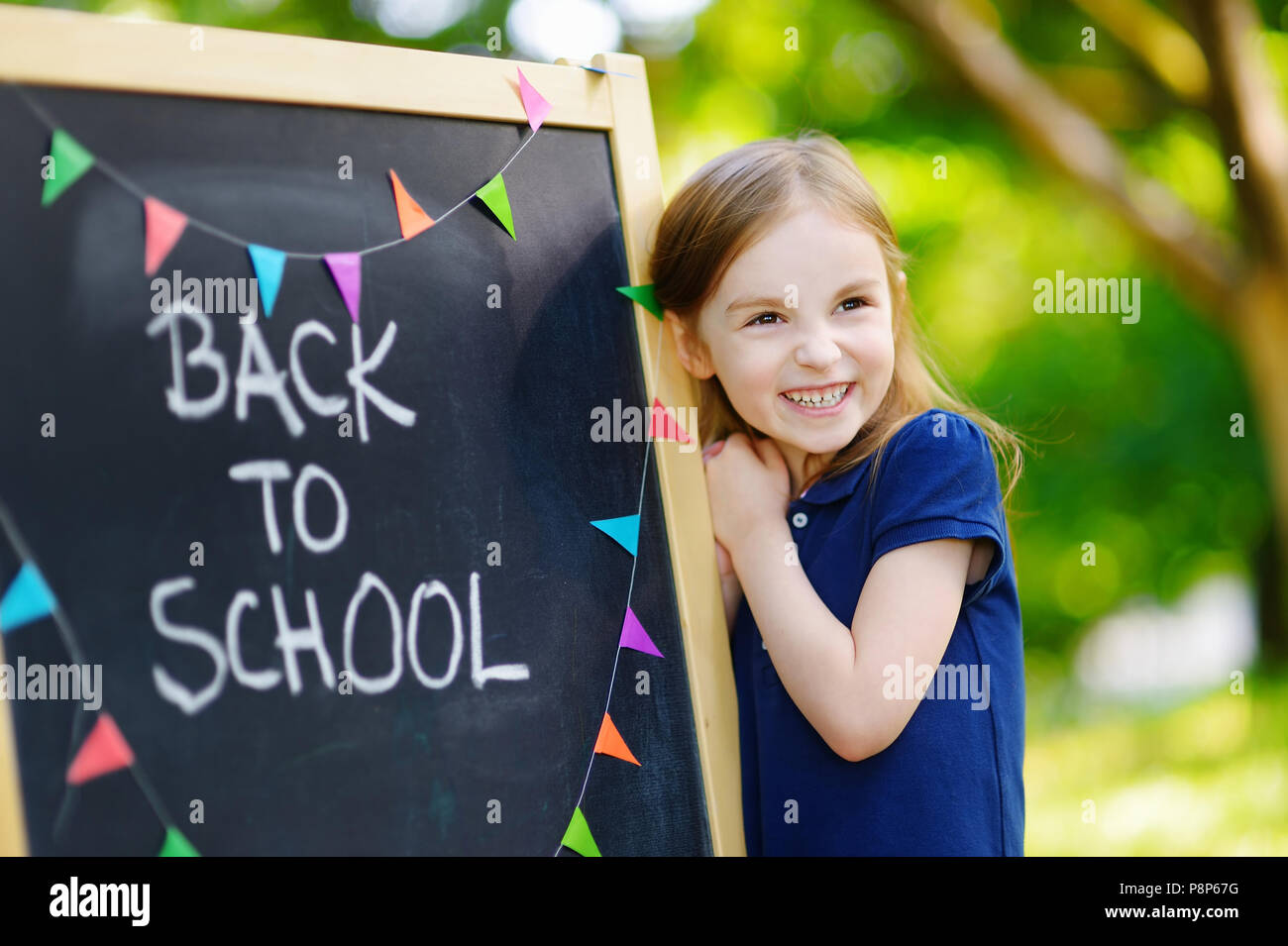 Adorable little schoolgirl feeling very excited about going back to ...
