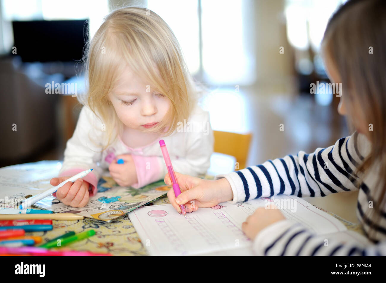 Two little sisters drawing and learning together at home Stock Photo ...