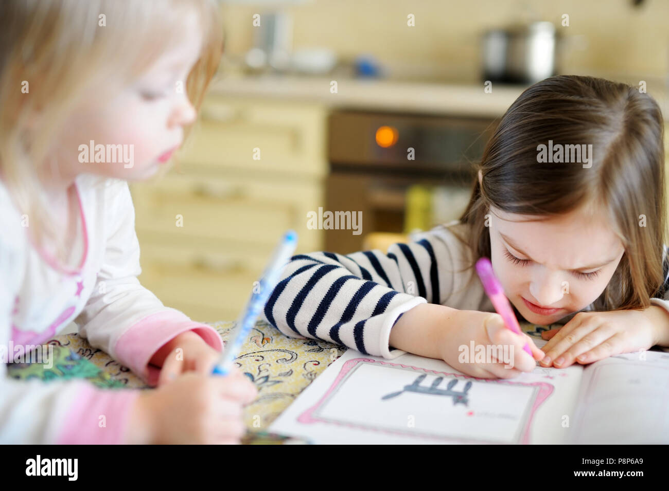 Two little sisters drawing and learning together at home Stock Photo ...