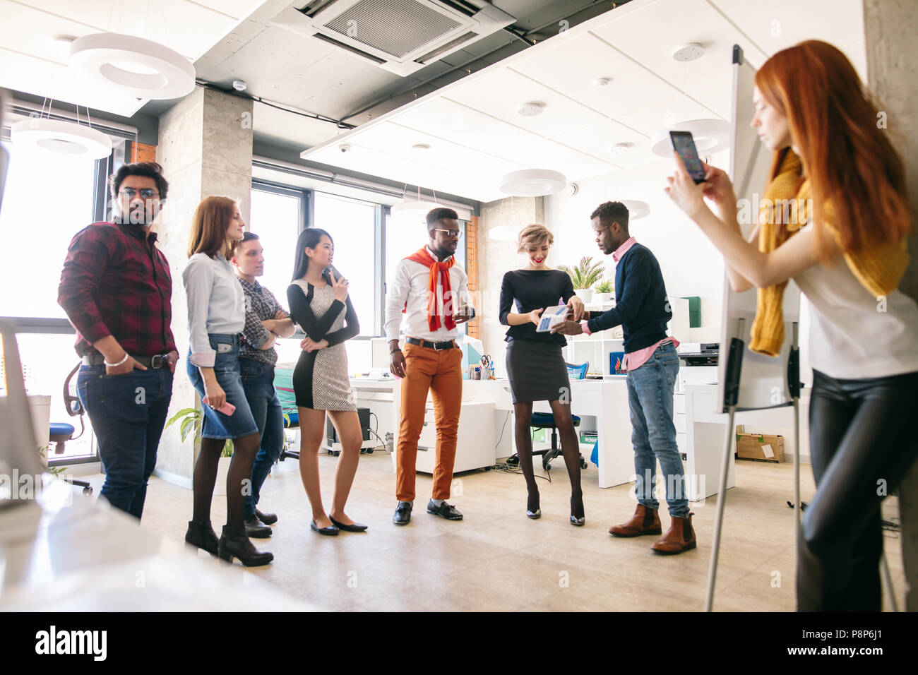 Ginger woman is taking photo of mixed race workshop for young business ...