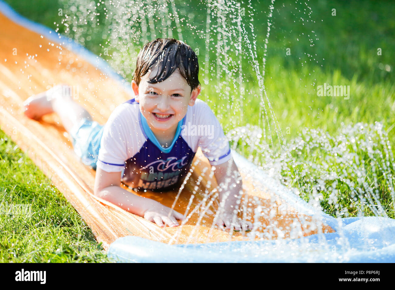 Boy sliding on Slip n slide in yard in the summer. Photo credit ...