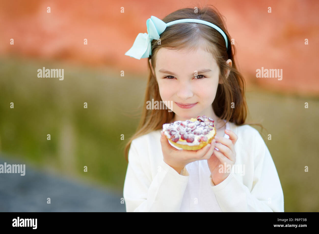 Adorable little girl eating fresh sweet strawberry cake outdoors on ...